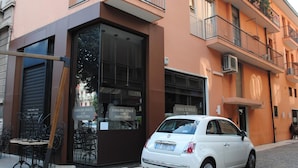 Um carro branco estacionado em frente a um edifício com uma placa que diz 'Casa del Dolce Caffe Pasticceria'.