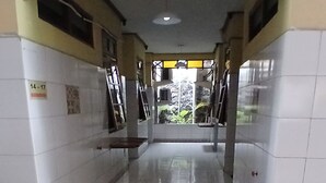 Corredor com paredes revestidas de azulejos e um tapete vermelho que leva a uma escada.