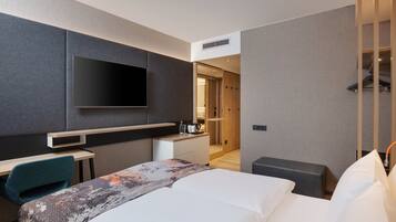 Quarto de hotel moderno com uma cama grande, escrivaninha, televisão de tela plana e closet espaçoso.