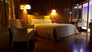 Quarto com cama, uma cadeira, mesa de cabeceira e espelho.