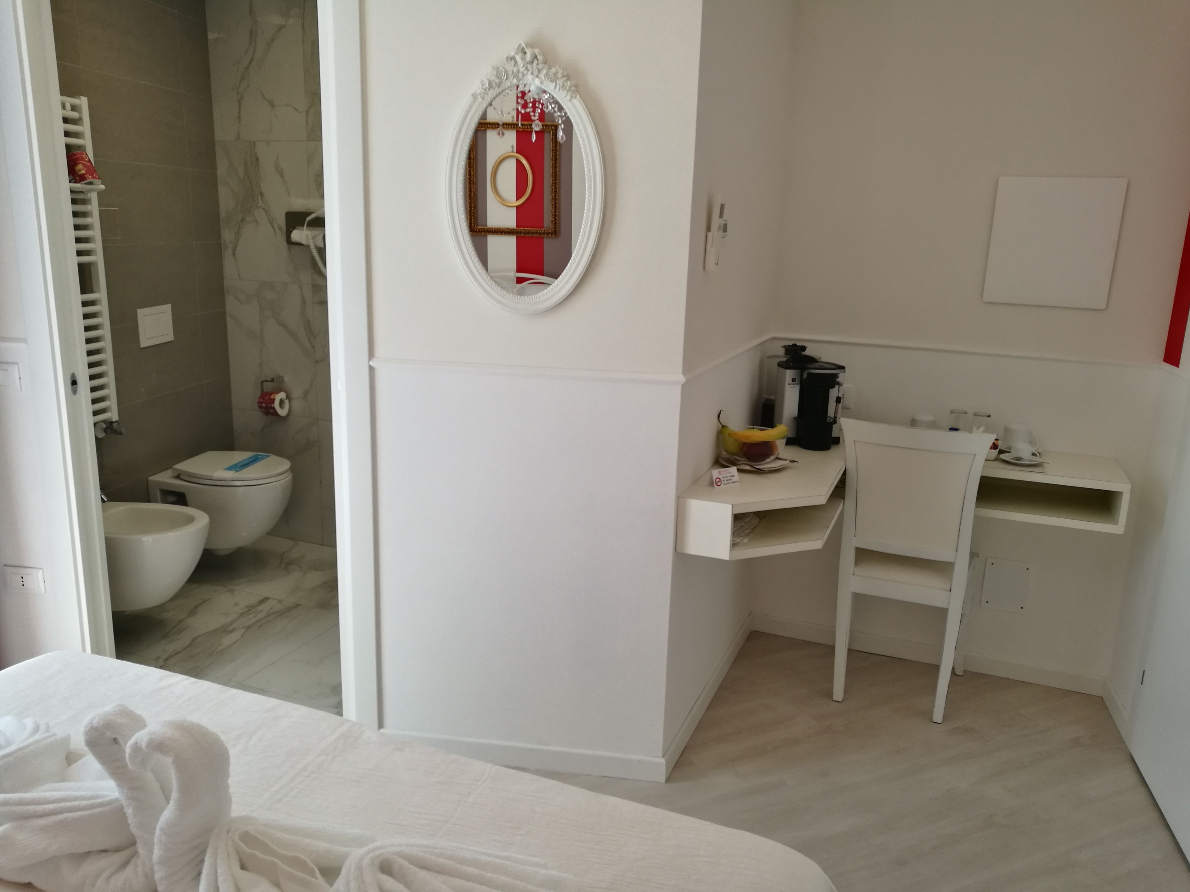 Quarto de hotel com cama, uma secretária pequena com cafeteira, sanita e área de duche.