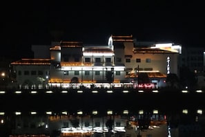 Um edifício com vários andares e uma entrada imponente, refletindo na água em frente.