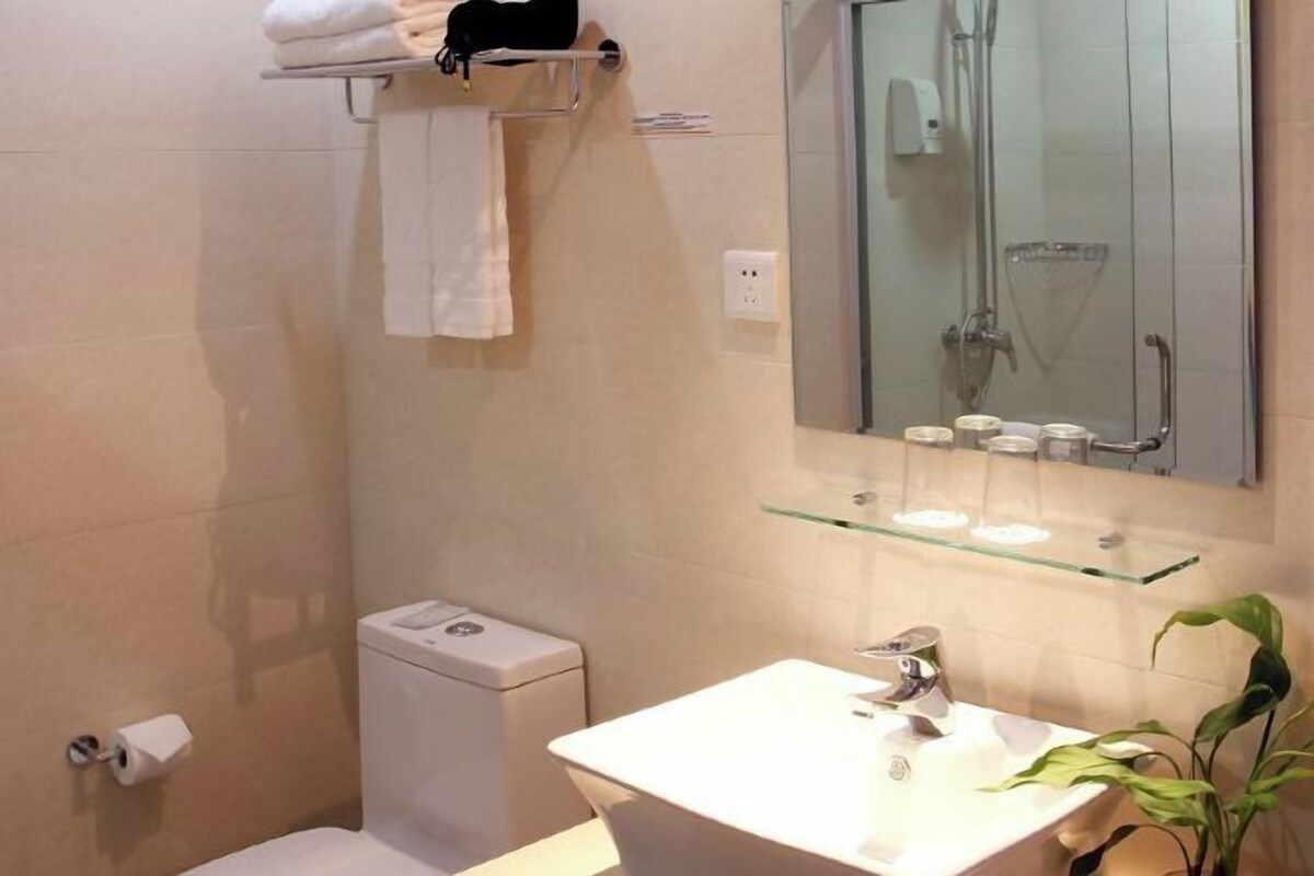Casa de banho com sanita, lavatório, espelho e porta-toalhas.