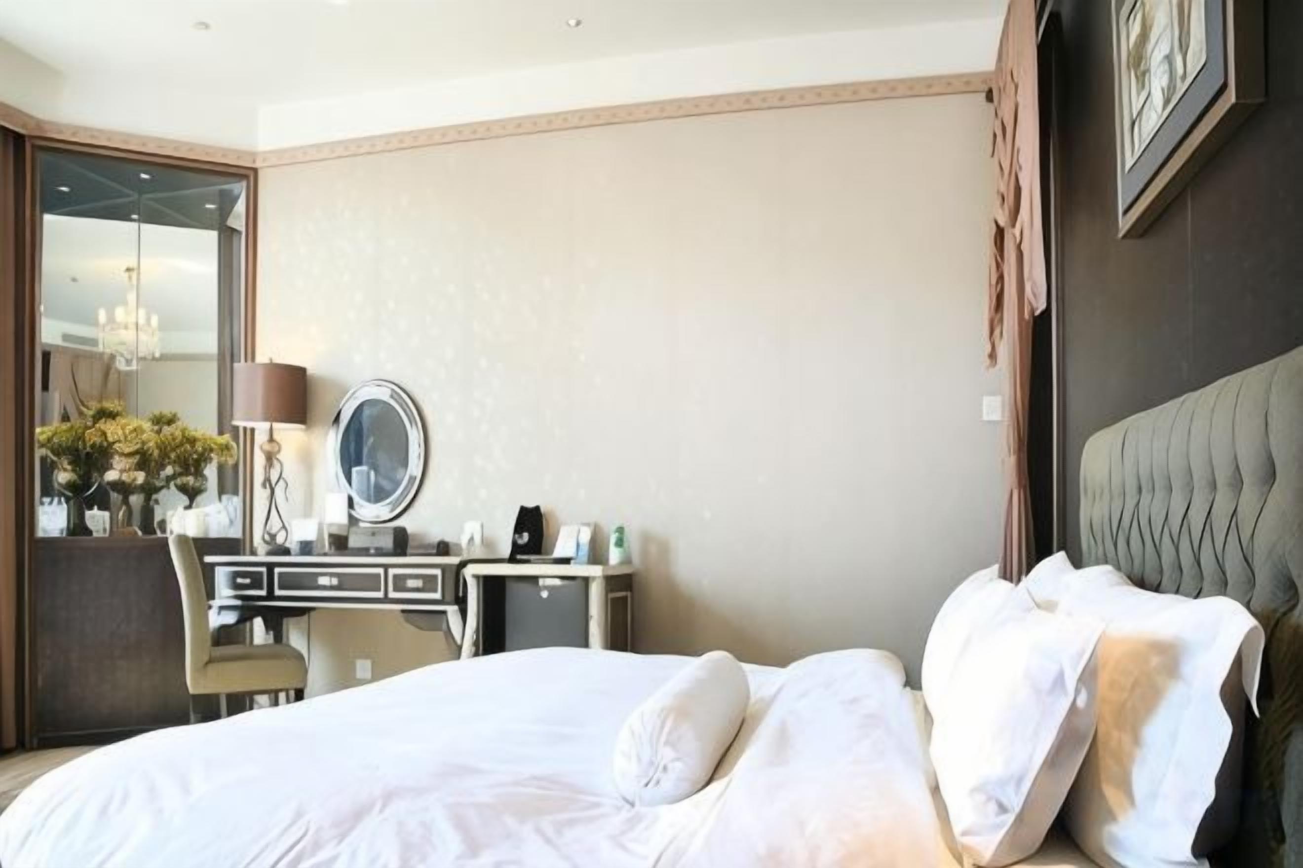 Quarto de hotel com cama, escrivaninha com espelho e uma cadeira.