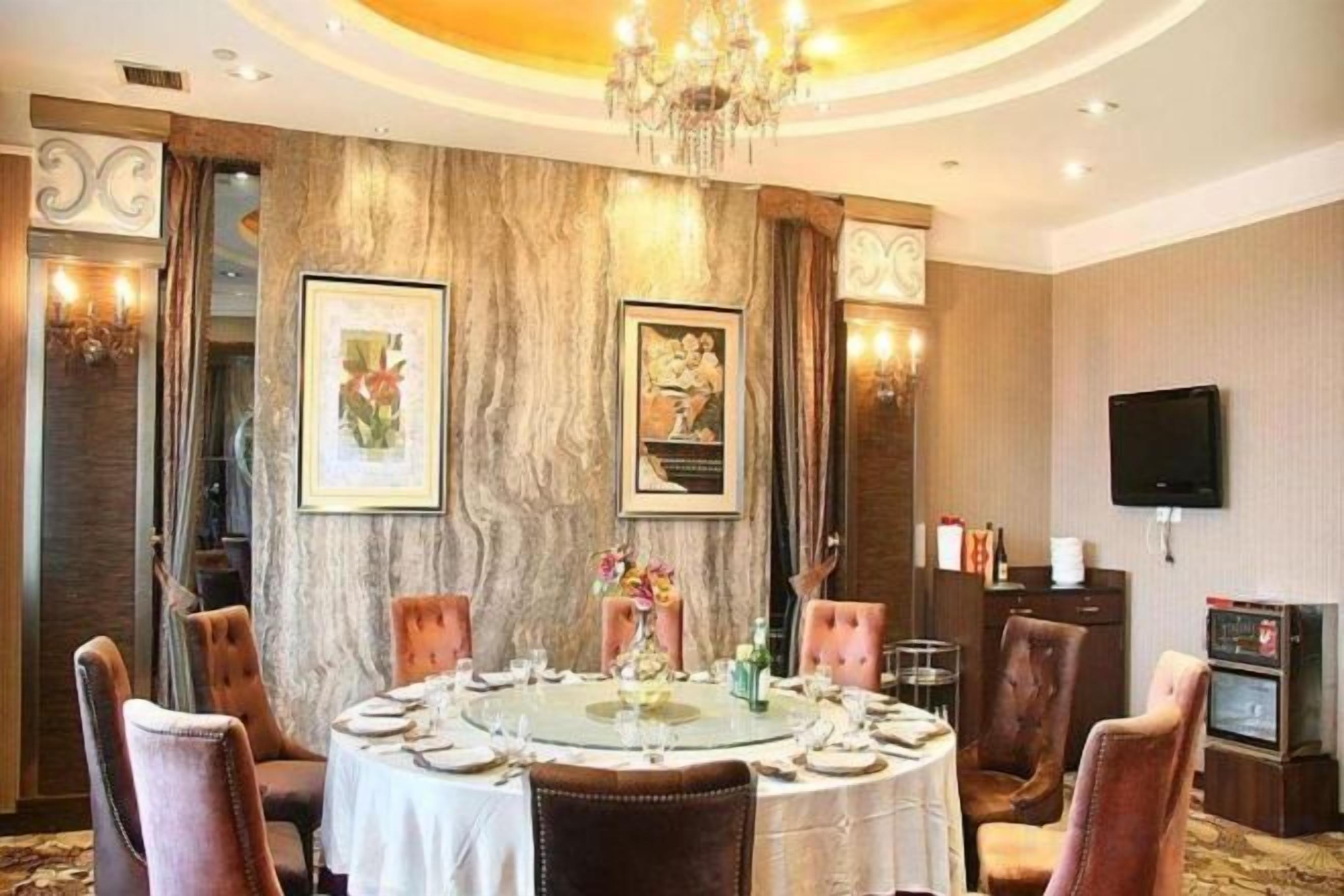 Uma sala de jantar com uma mesa redonda posta para seis pessoas, rodeada por seis cadeiras, e um candelabro sobre a mesa.