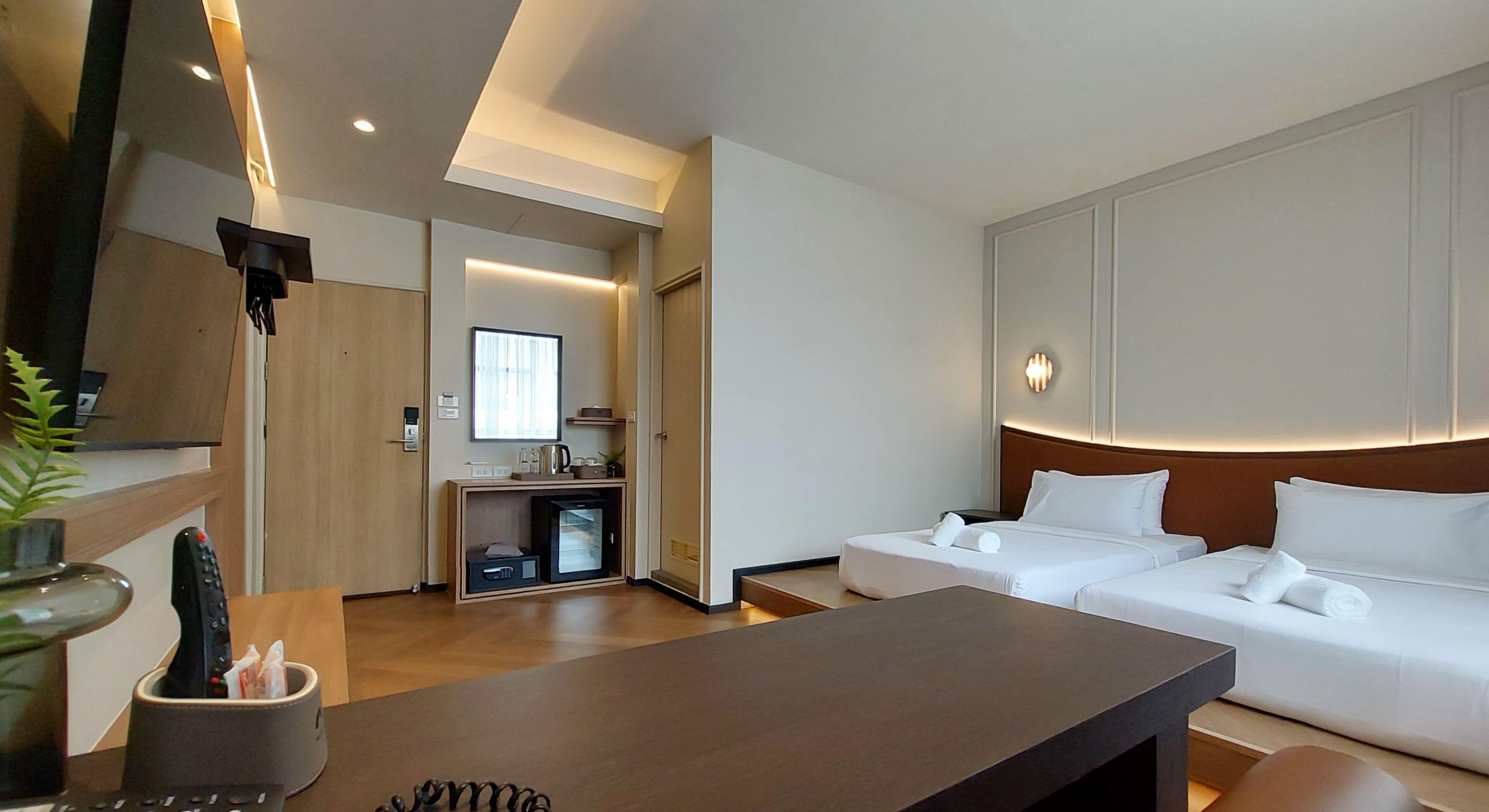 Quarto de hotel moderno com sofá, mesa, cozinha compacta e banheiro.