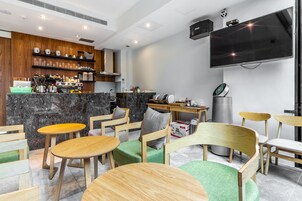 Uma cozinha moderna com armários de madeira, bancada de mármore e TV de tela plana na parede.
