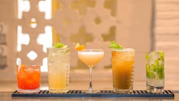 Um bar com cinco coquetéis diferentes, cada um decorado com um limão e hortelã, exibidos em uma bandeja preta.