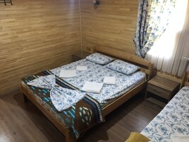 Quarto com painéis de madeira, uma cama, uma mesa de cabeceira e uma janela com cortinas.