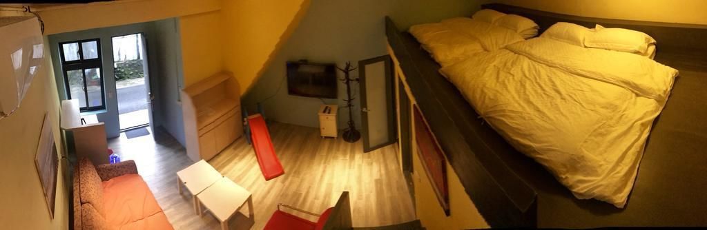 Quarto com cama, televisão e escrivaninha.