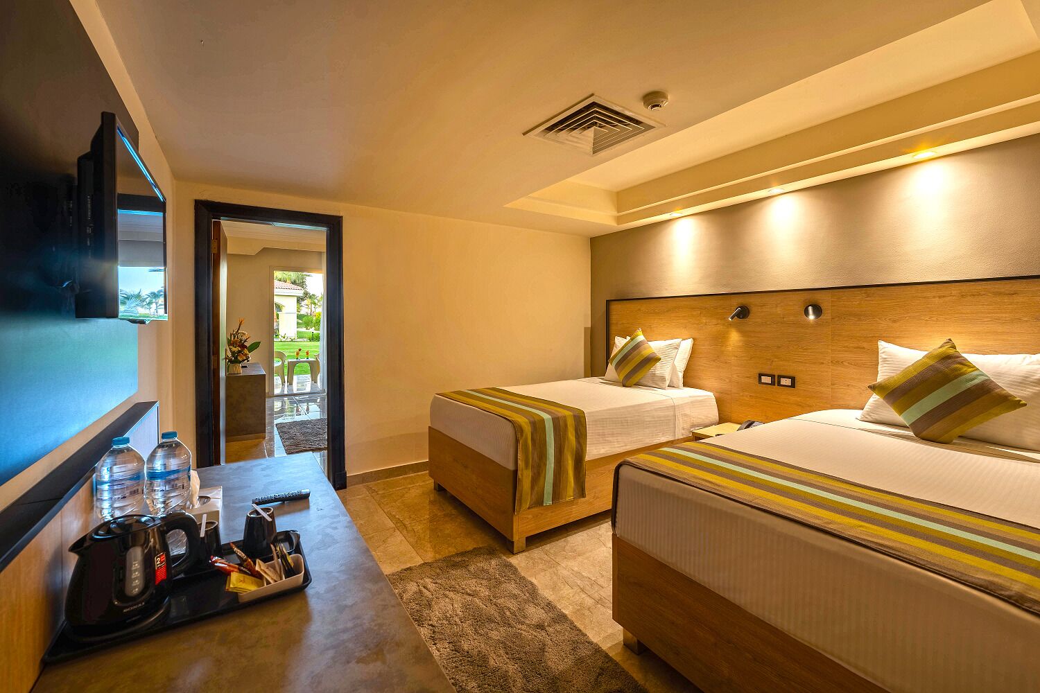 Quarto de hotel com duas camas, televisão, máquina de café e mini-bar.