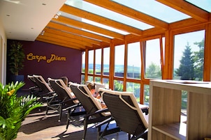Quarto ensolarado com cadeiras de vime, teto de madeira e grandes janelas com vista para o exterior.