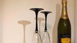 Uma garrafa de vinho Valdo Prosecco, dois copos de vinho e um pedaço de tecido sobre uma mesa.