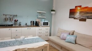 Um espaço de estar compacto com cozinha compacta, área de jantar e sofá.