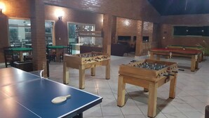 Uma área de lazer com mesas de pebolim e tênis de mesa.