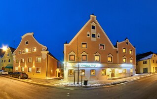 Um hotel de estilo europeu tradicional com uma entrada imponente, várias janelas e terreno coberto de neve.