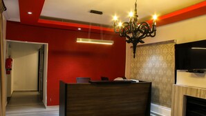 Uma área de recepção moderna com um balcão de madeira, um candelabro, uma TV de tela plana e uma lareira.