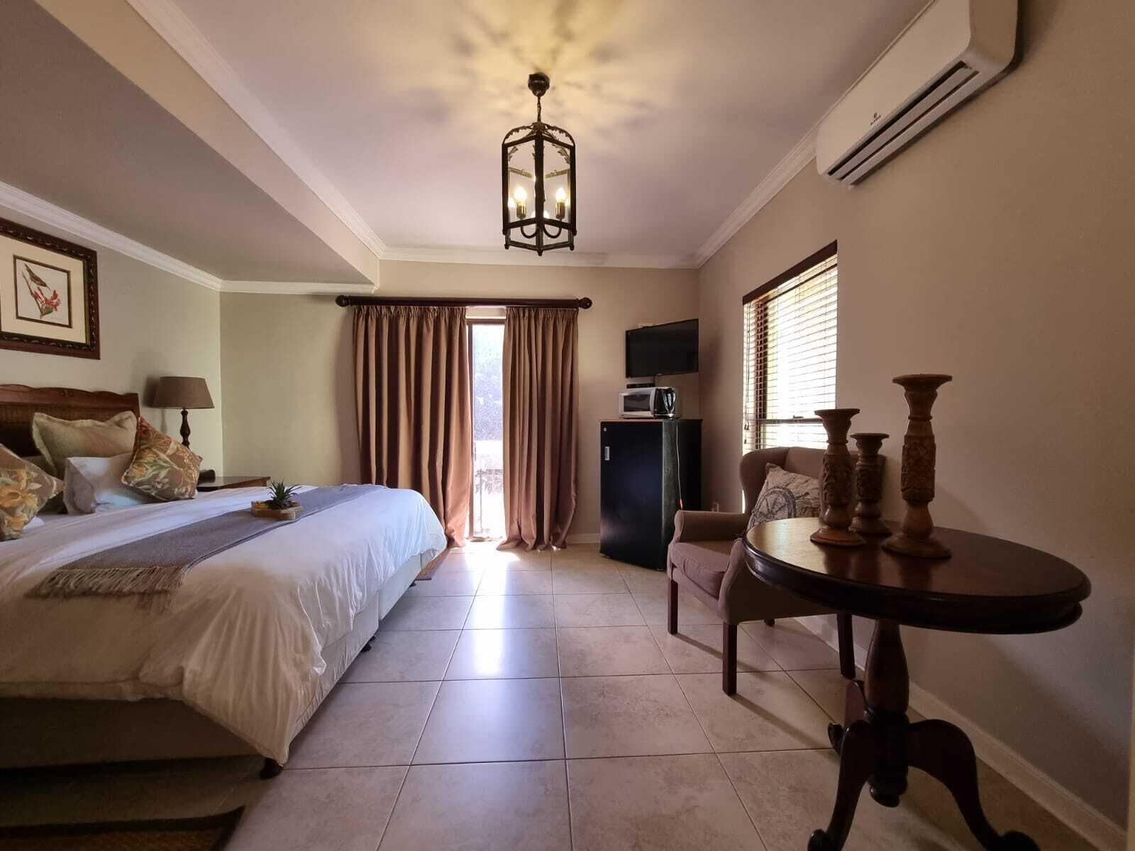 Quarto de hotel com uma cama grande, uma escrivaninha com cadeira, televisão e janela com persianas.