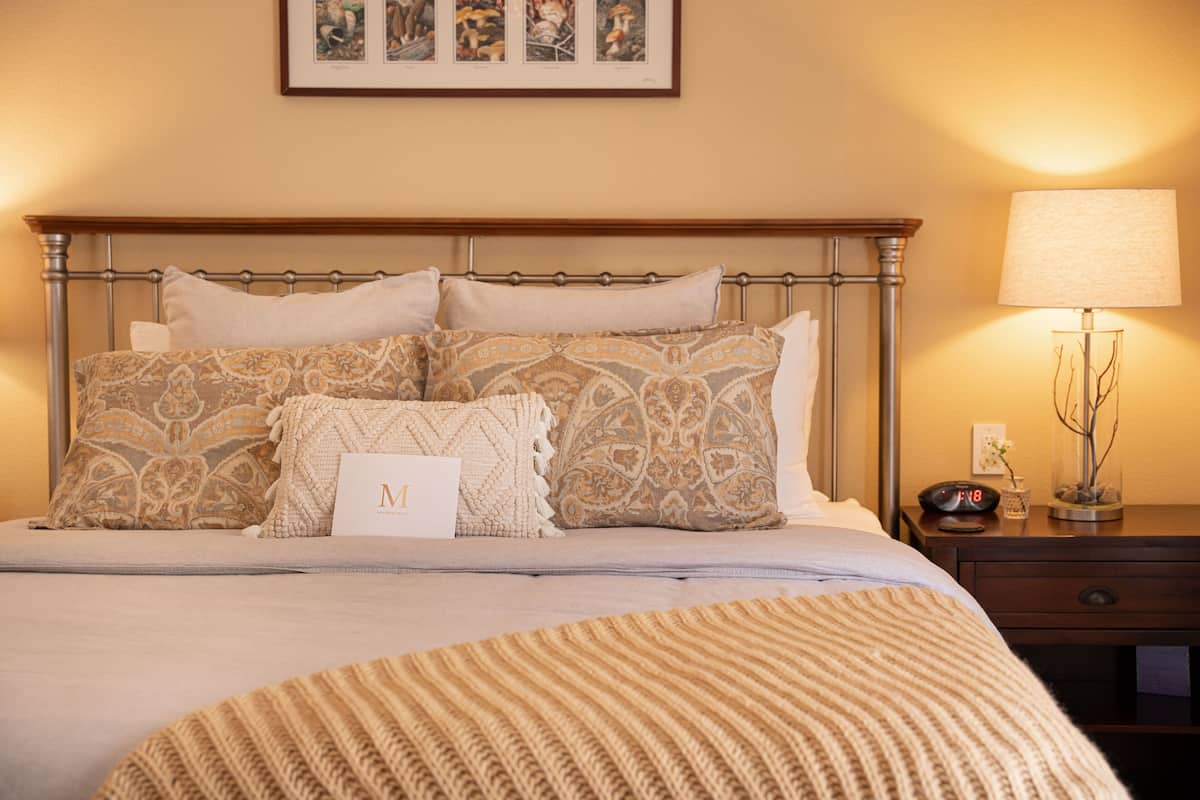 Cama bem arrumada com almofadas estampadas e cabeceira decorativa.