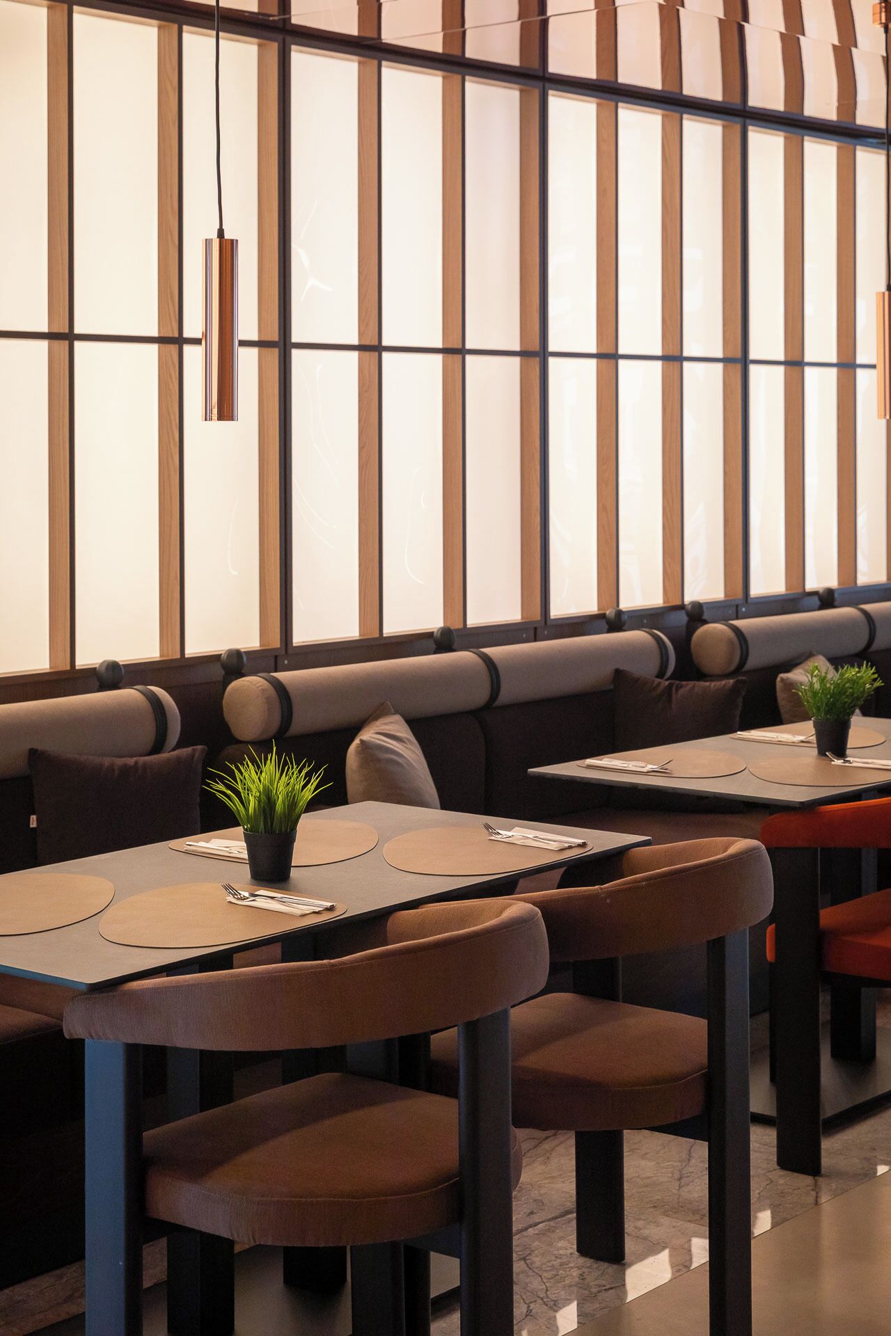 Interior de restaurante com cabines e mesas, algumas com plantas.