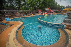 Uma piscina com borda azulejada, um escorregador e brinquedos infláveis.