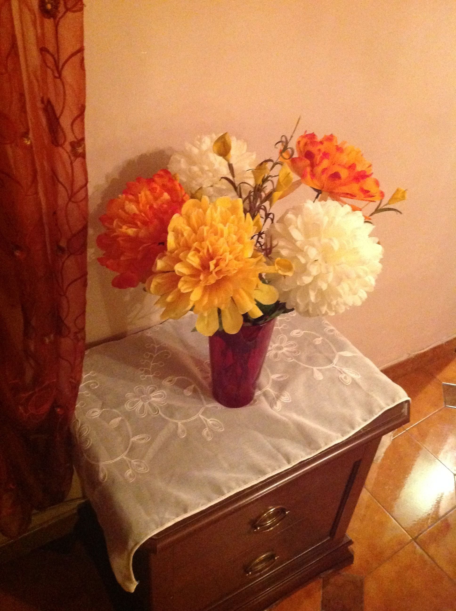 Um vaso com flores sobre uma pequena mesa.