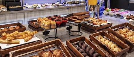 Buffet com diversos doces e produtos de pastelaria expostos em caixas de madeira.