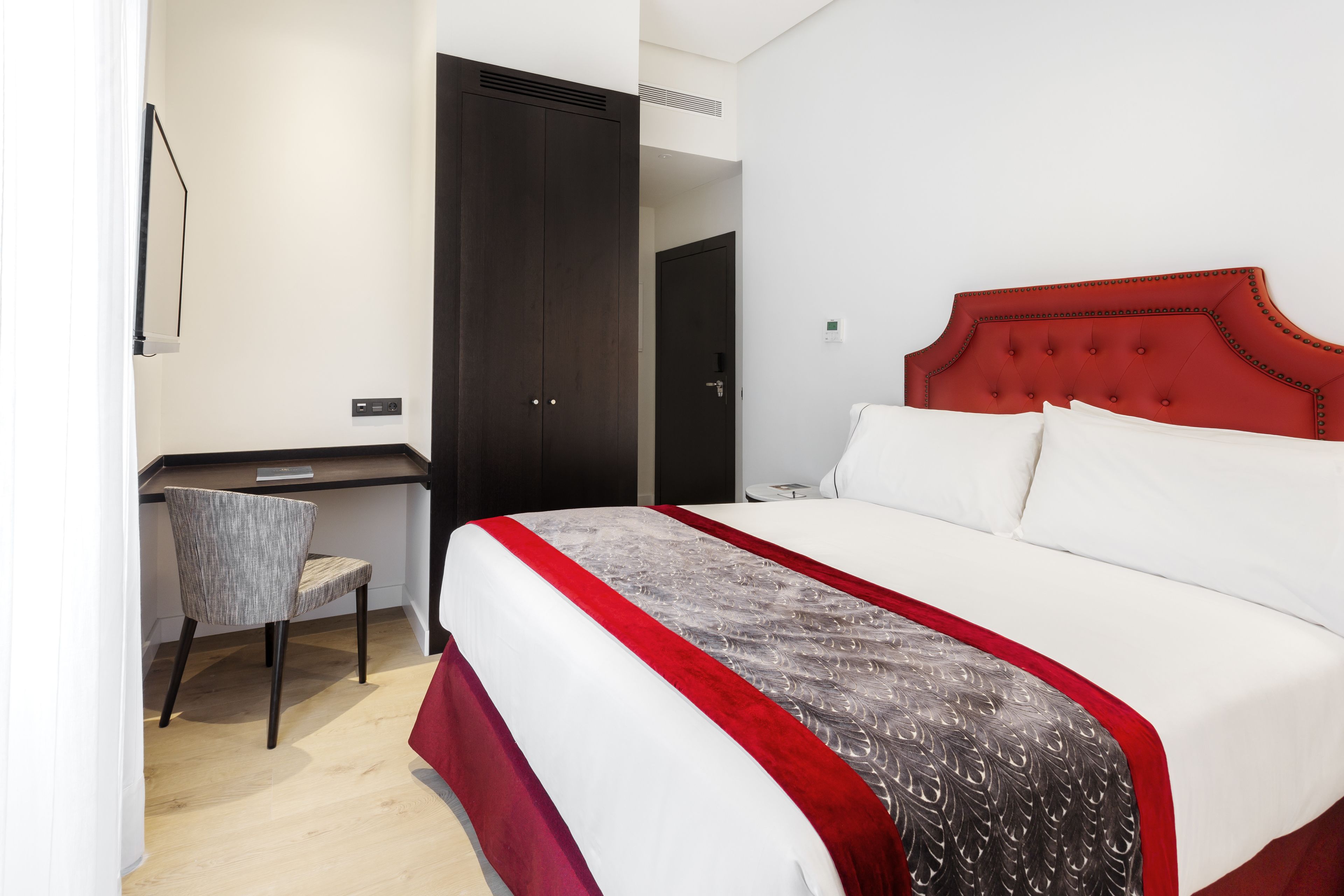 Quarto de hotel com uma cama, uma mesa e uma cadeira.