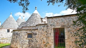 Um edifício de pedra com telhado cónico, uma pequena janela e uma porta com portão de metal.