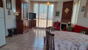 Uma sala de jantar com uma mesa posta para quatro pessoas, uma televisão e um armário com espelho.