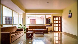 Uma sala de estar ampla com um sofá marrom, uma mesa de centro e uma pequena mesa lateral.