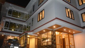 Hotel de vários andares com design moderno, com grandes janelas e entrada bem iluminada.