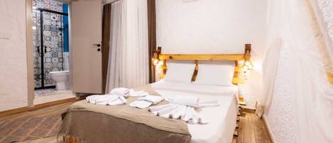 Quarto de hotel com cama, banheiro com chuveiro e um aparelho de ar condicionado na parede.