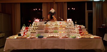 Uma mesa de sobremesas grande, com diversos bolos, doces e bebidas.