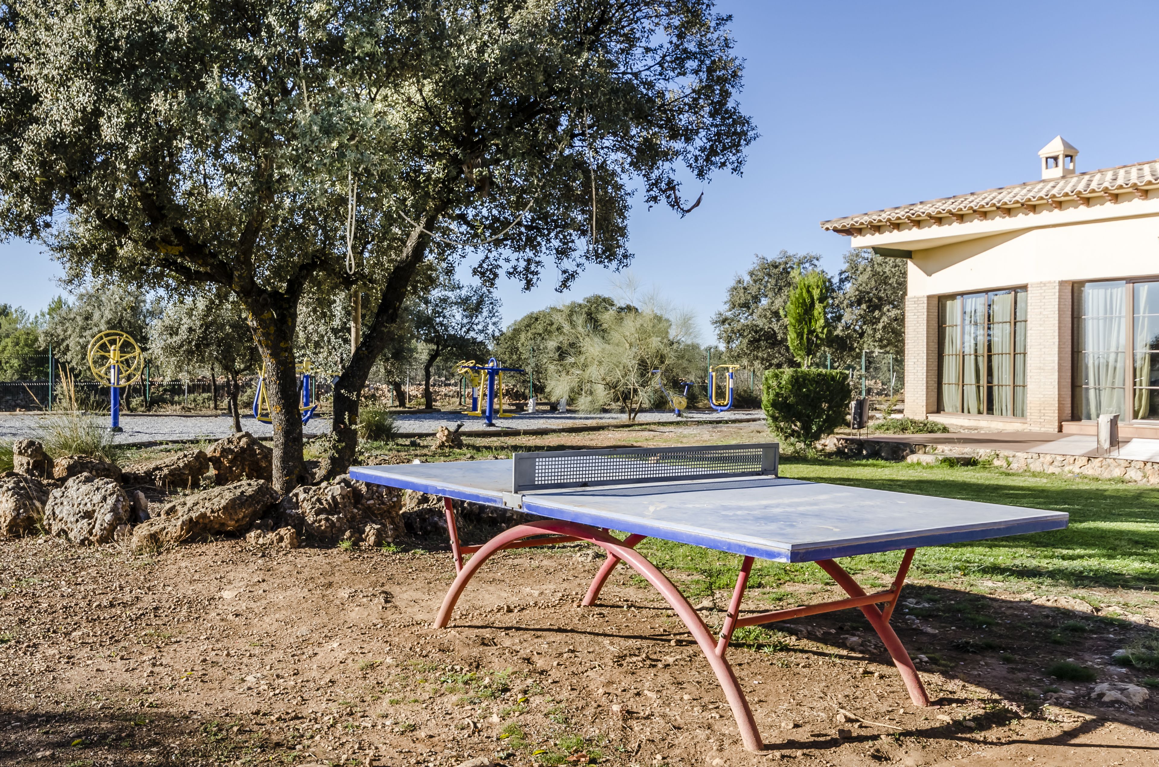 Mesa de tênis de mesa ao ar livre em um parque, com um edifício ao fundo.