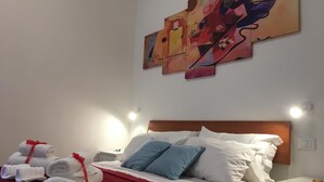 Quarto de hotel com cama, almofadas, manta vermelha e toalhas ao lado.