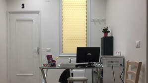 Um pequeno escritório com uma mesa, computador, cadeira e um vaso de planta.