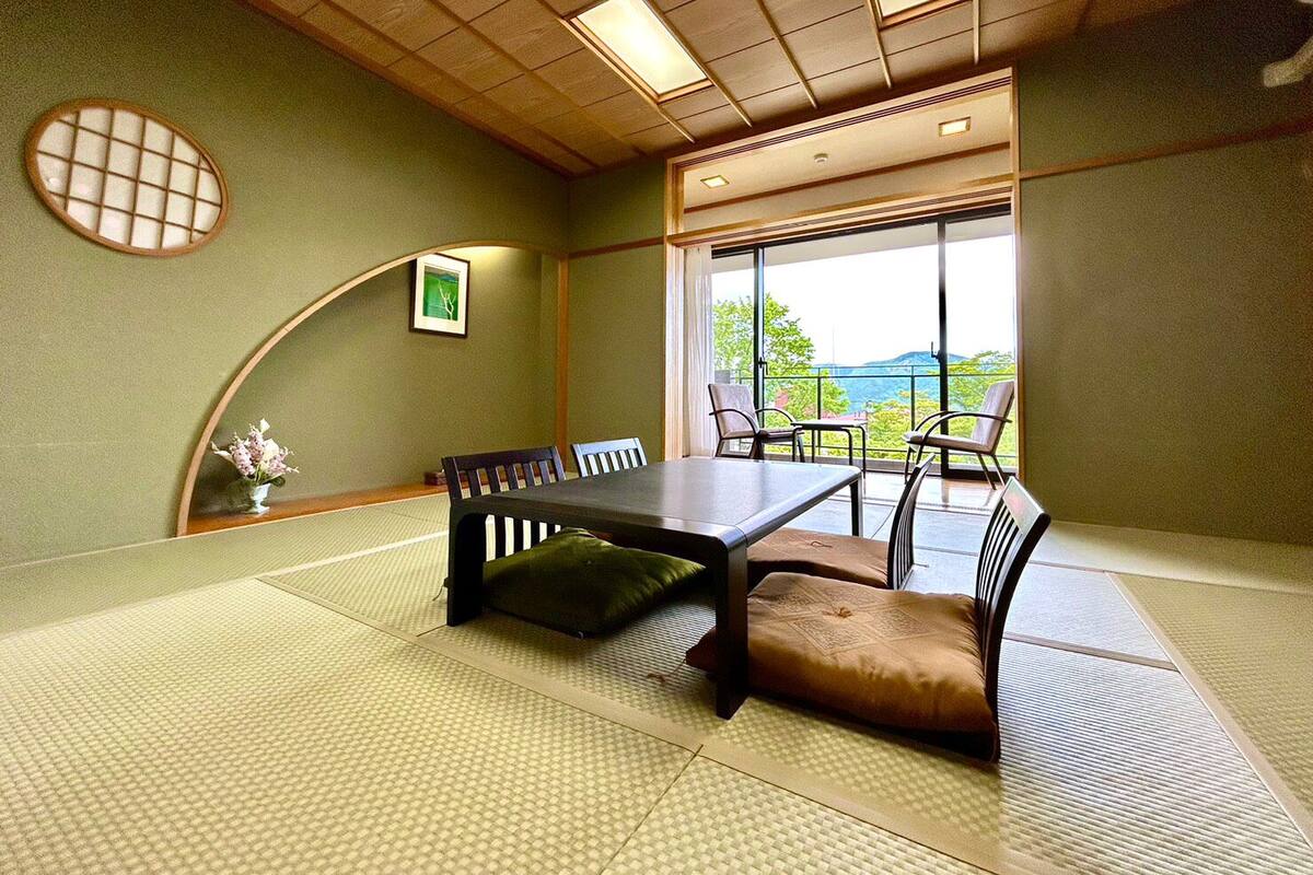 Uma sala de reuniões tradicional japonesa com piso de tatame, uma mesa baixa e biombos de papel.