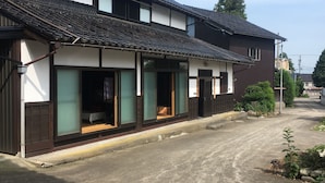 Uma casa japonesa tradicional com portas de correr, telhado telhado e um pequeno jardim.