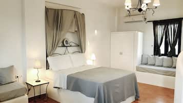 Quarto com cama, mesas de cabeceira, guarda-roupa, janela com cortinas e um candelabro.