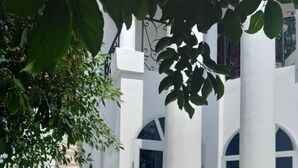 Um edifício branco com colunas e janelas em arco.