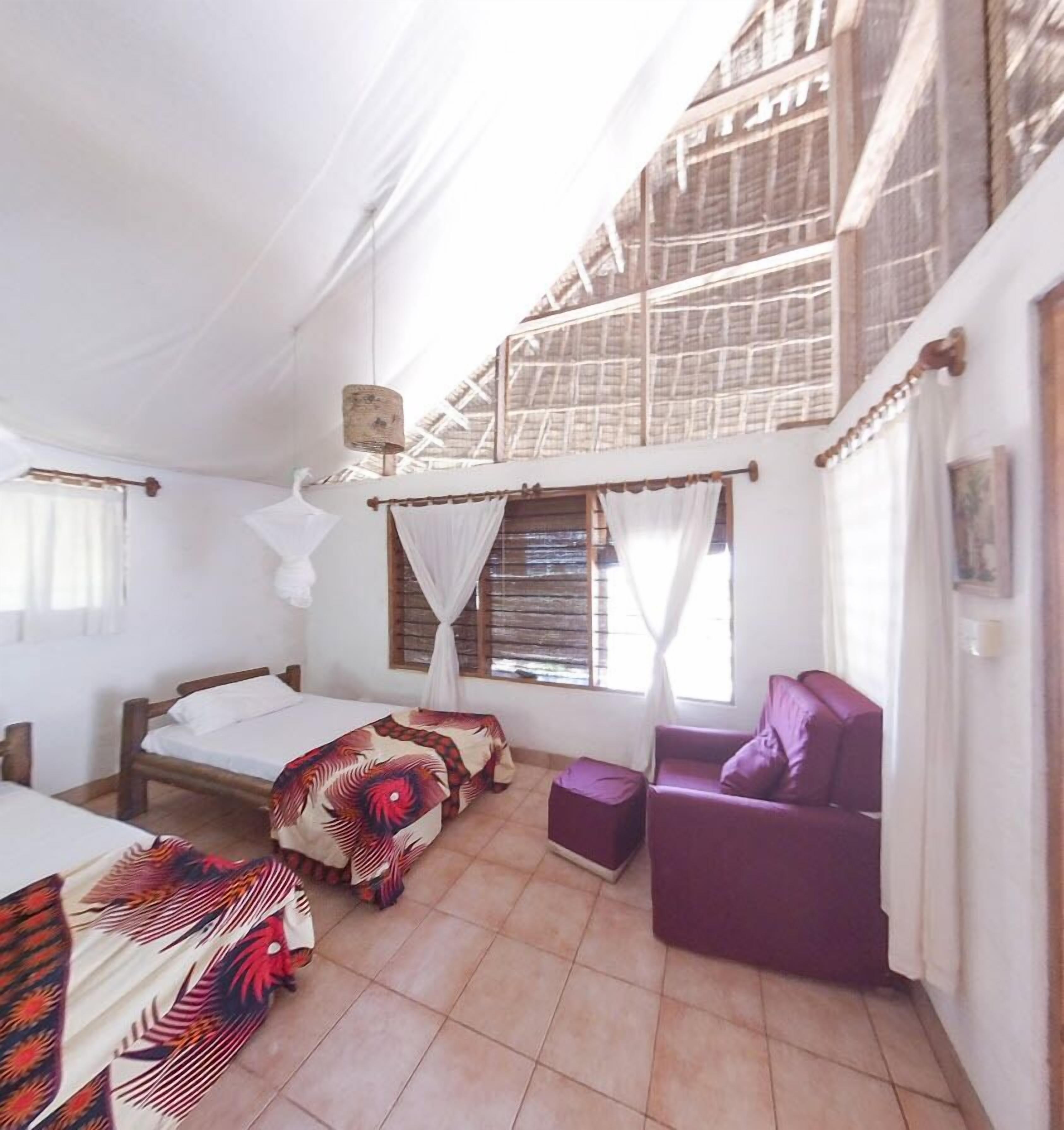 Um quarto com cama, sofá, uma mesinha e escada.