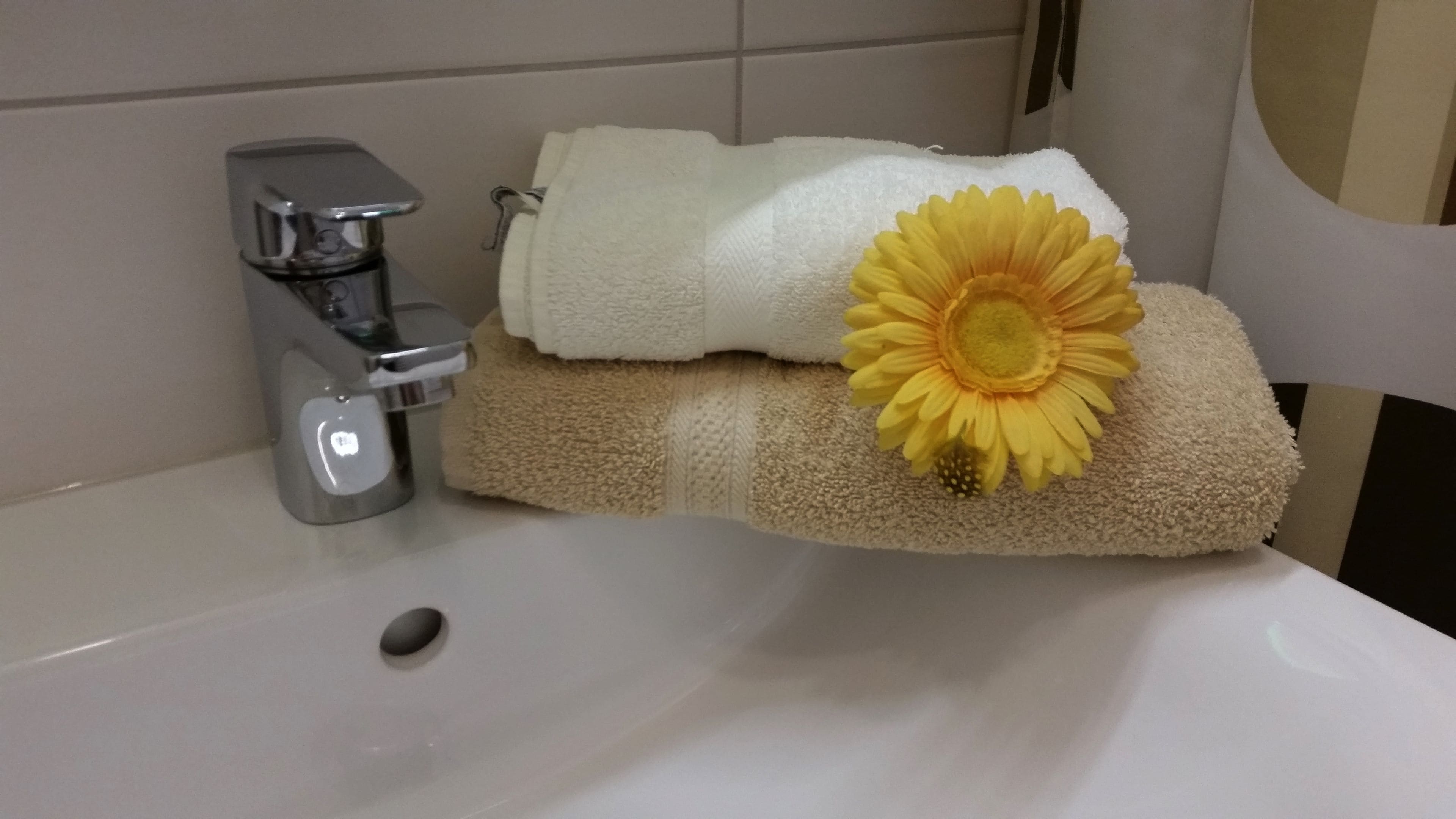 Uma pia de banheiro com uma toalha e uma flor decorativa.