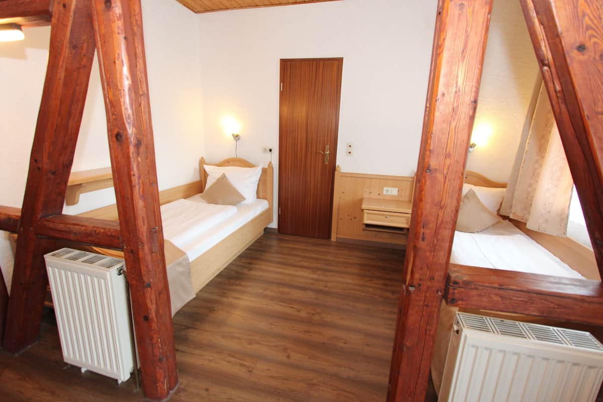 Quarto com duas camas de madeira, um guarda-roupa de madeira e um radiador.