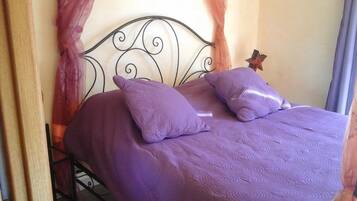 Cama com cabeceira, duas almofadas e cortinas leves.