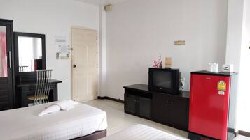 Quarto de hotel com cama, escrivaninha, televisão e frigorífico.