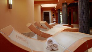 Uma área de spa com vários espreguiçadeiras, um porta-toalhas e um pilar com padrão texturizado.