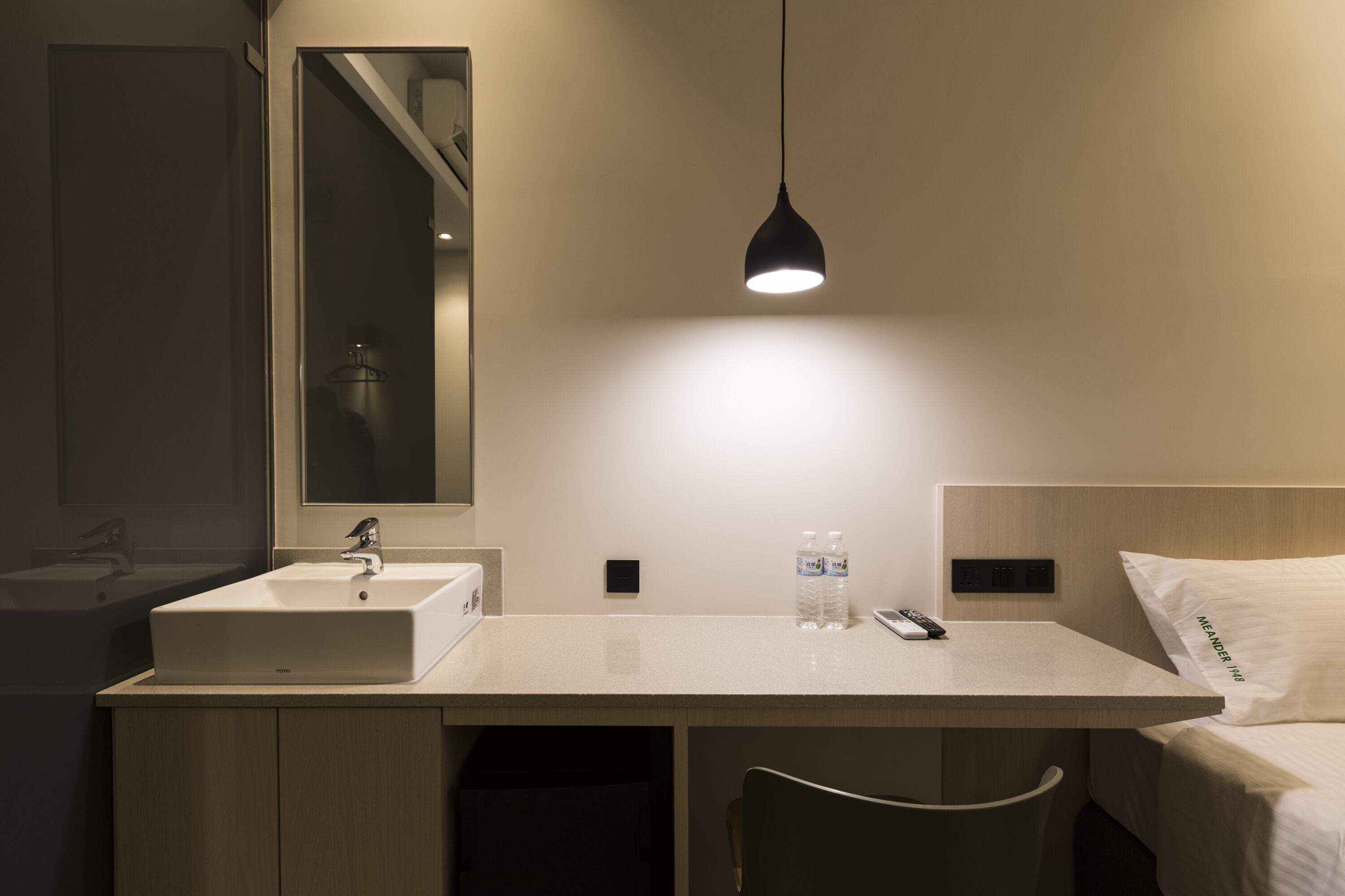 Casa de banho de hotel moderna com um espelho grande, uma pia e uma mesa de cabeceira com uma lâmpada.
