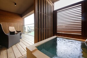 Uma área de spa com deck de madeira, hidromassagem e espaço de estar com vista para a cidade.
