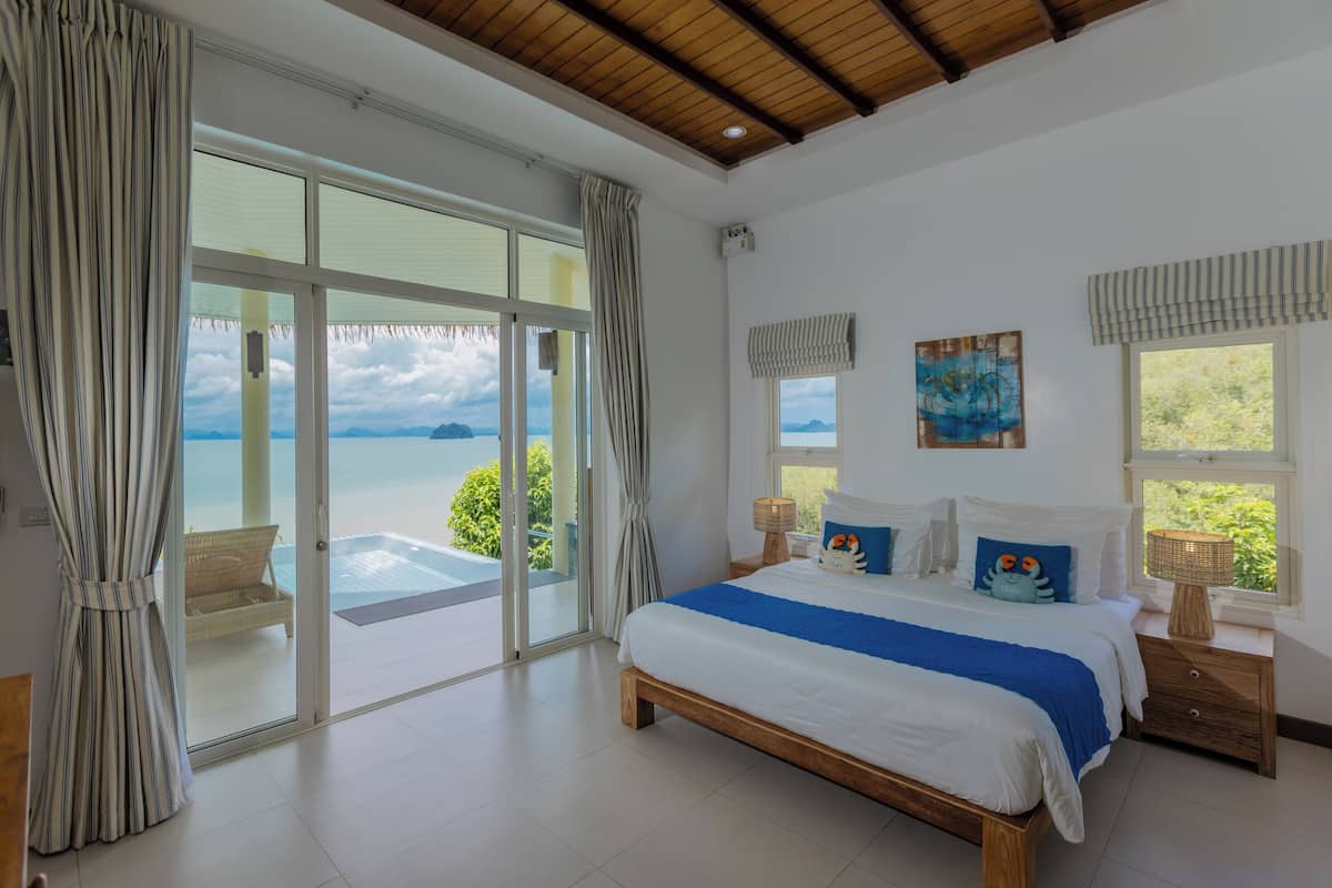 Quarto com uma cama grande, vista para o mar e varanda.